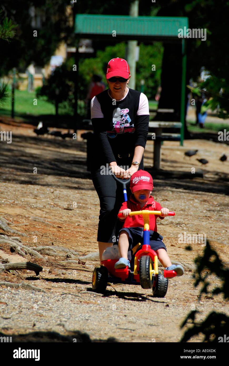 Mother pushing child on a toy bike Stock Photo - Alamy