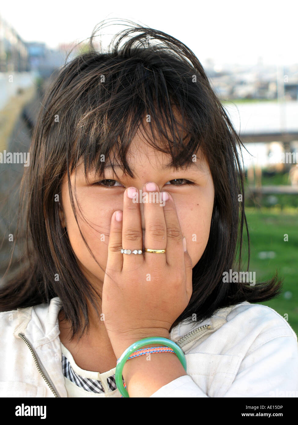 Smiling young Vietnamese girl with hand in front of face looking at the ...