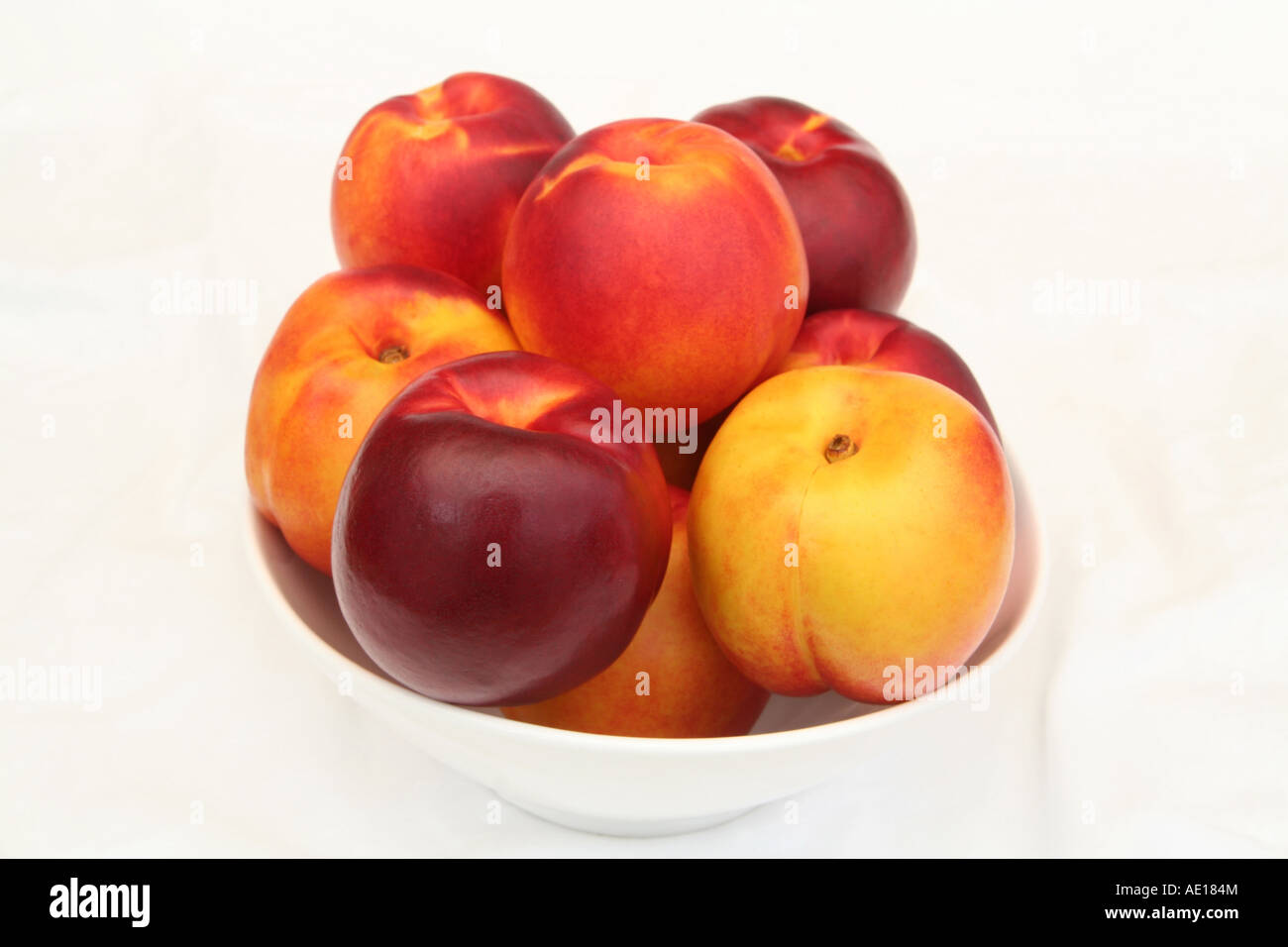 Nectarines in a white bowl plain light background landscape view ...