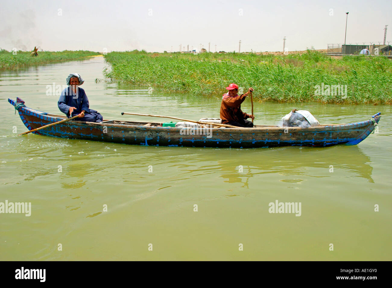 Iraqi civilians paddle their locally made canoe along a waterway ...