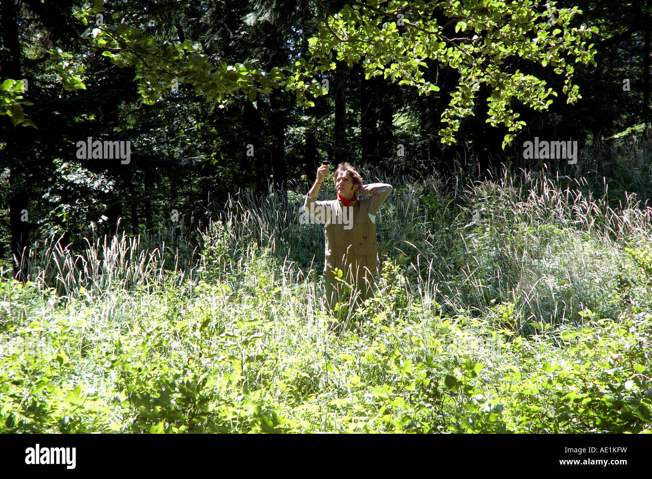 Young man taking position reading with GPS receiver in middle of forest ...