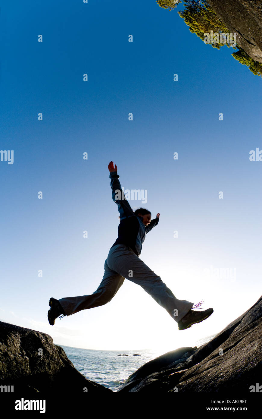 A woman leaps between two rocks at East Sooke Park near Victoria, BC ...