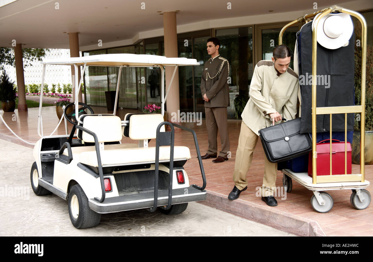 Bellboy delivering luggage to hotel with doorman standing by Stock ...