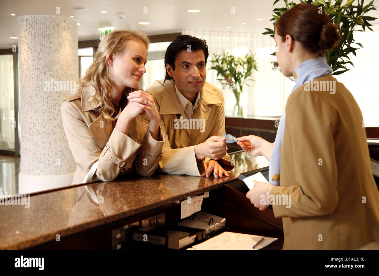 Couple checking in at hotel reception Stock Photo - Alamy