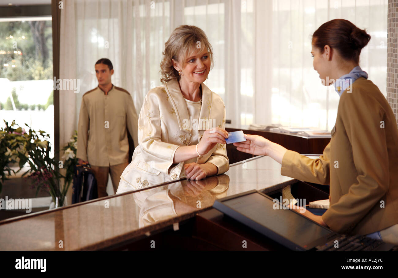 Woman checking in at the hotel reception desk Stock Photo - Alamy