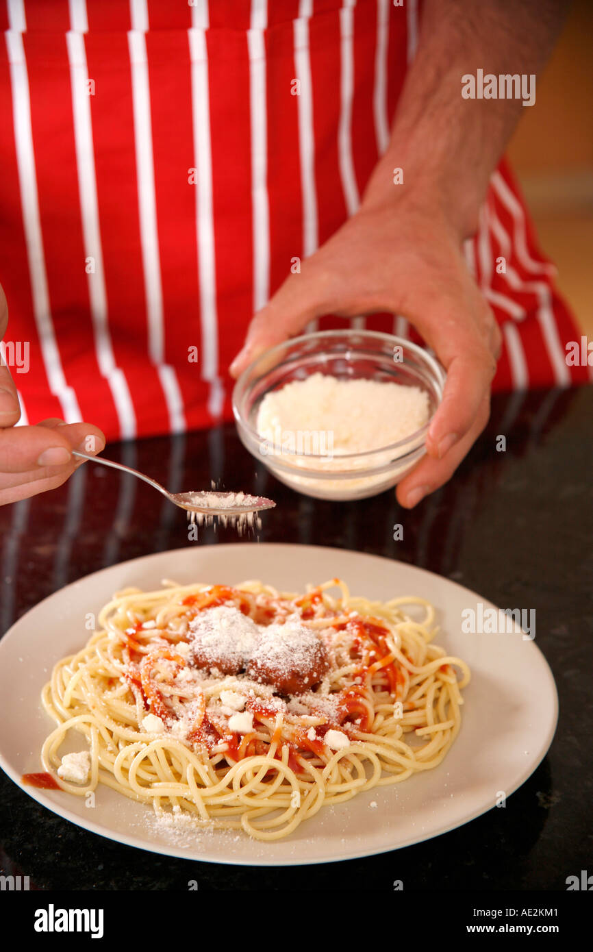 Man sprinkling cheese on spaghetti Stock Photo - Alamy