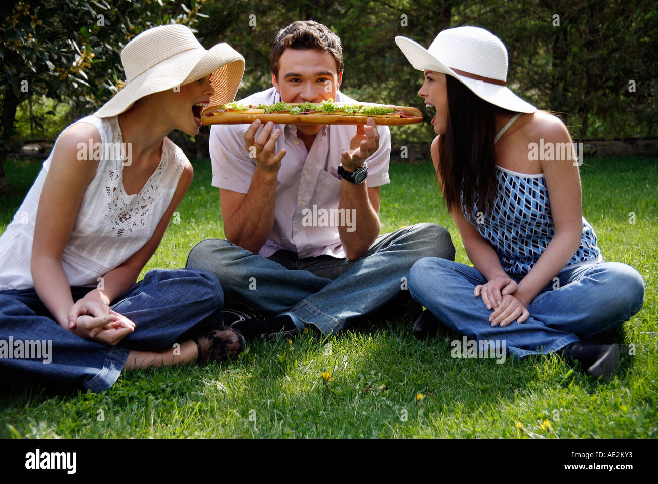 Three friends sharing a big sandwich Stock Photo - Alamy
