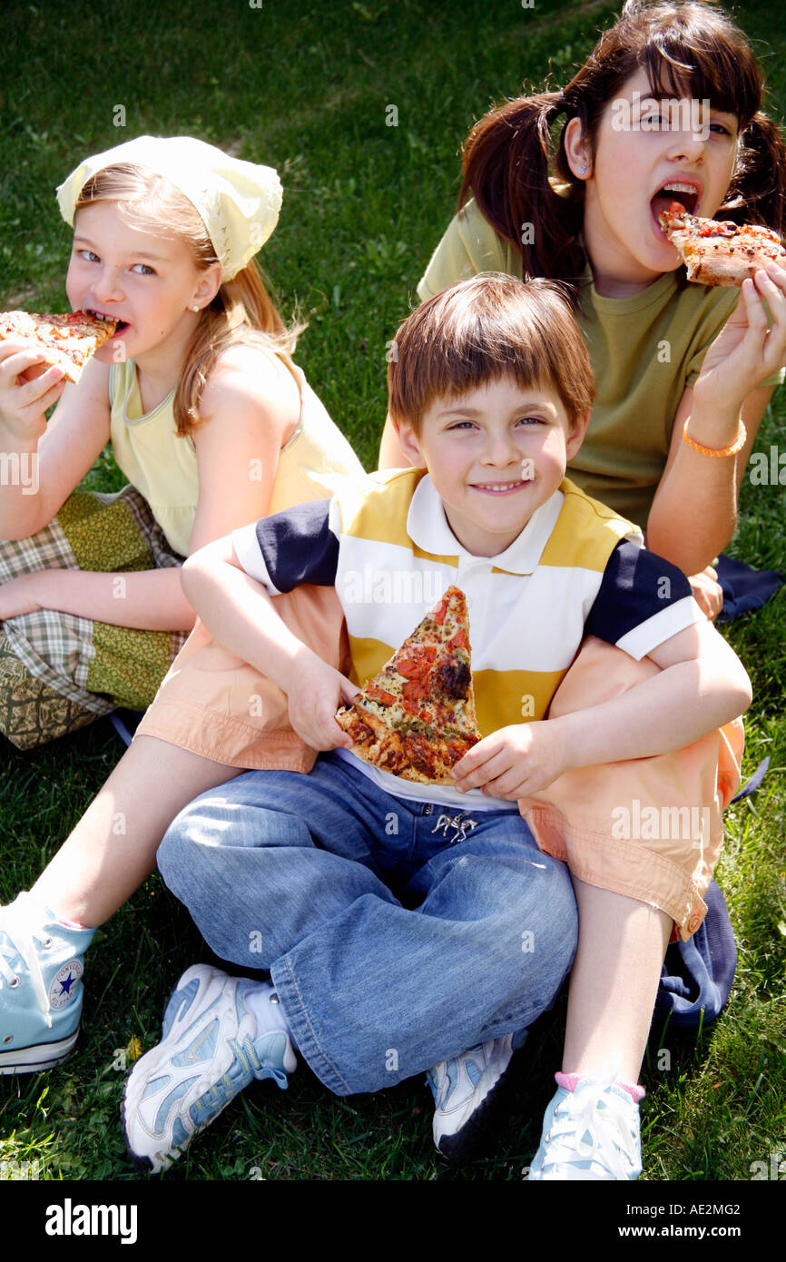 Three children eating pizza Stock Photo - Alamy