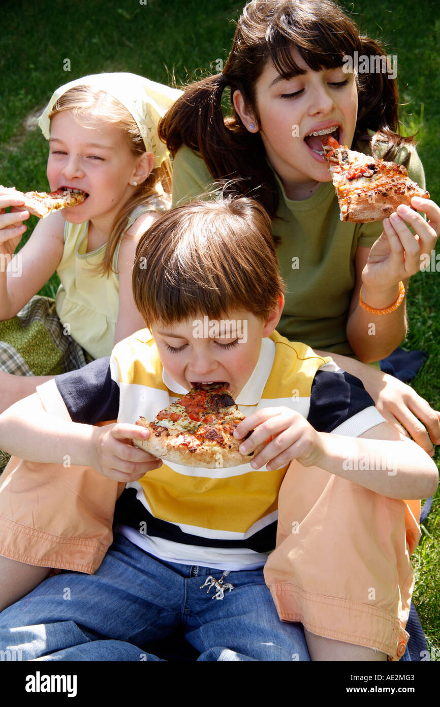 Three children eating pizza Stock Photo - Alamy