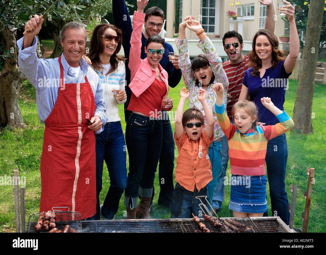 Father and son at barbecue grill with extended family having lunch in ...