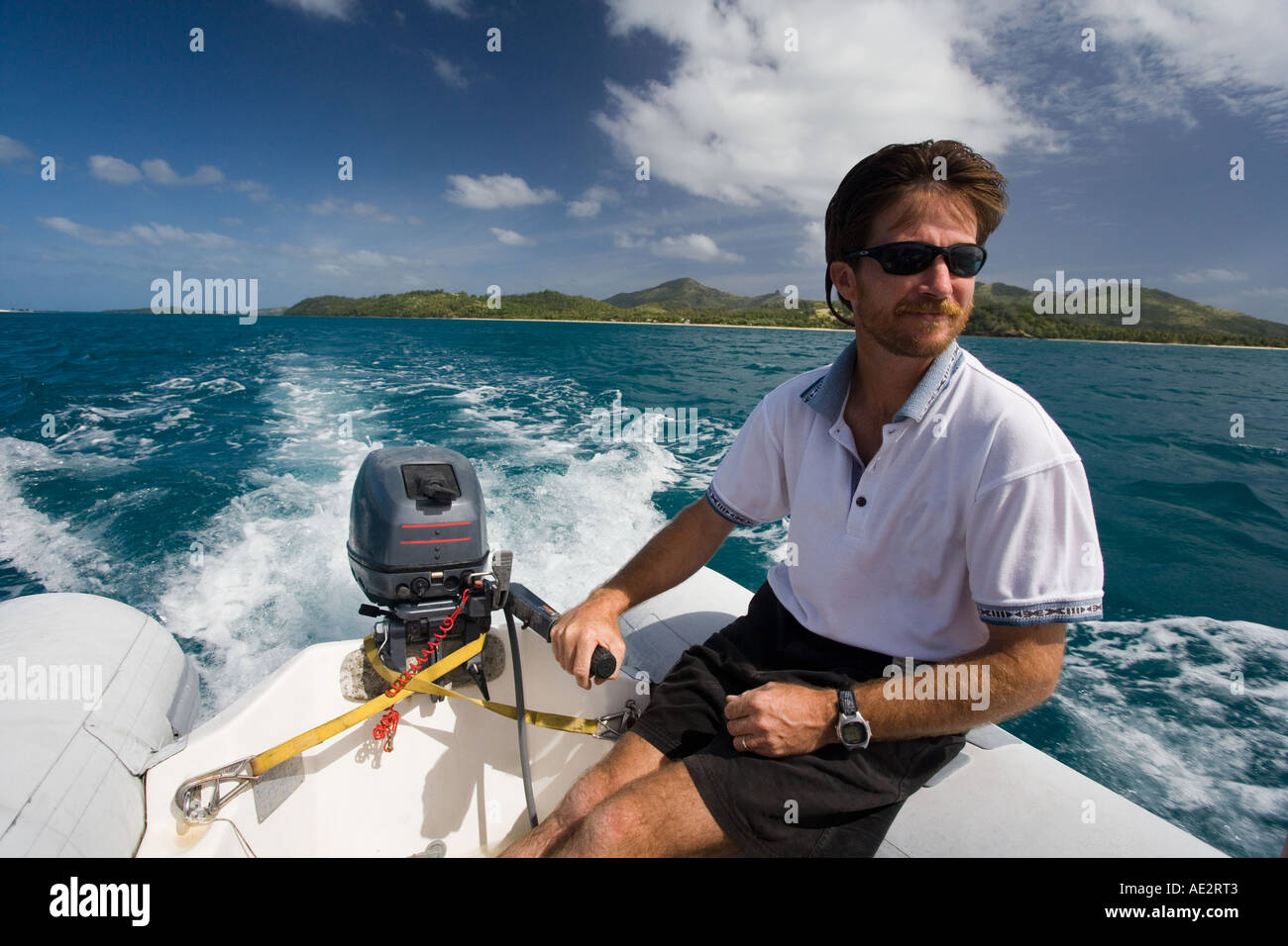 Man on outboard dinghy in the tropical waters of Fiji in South Pacific ...