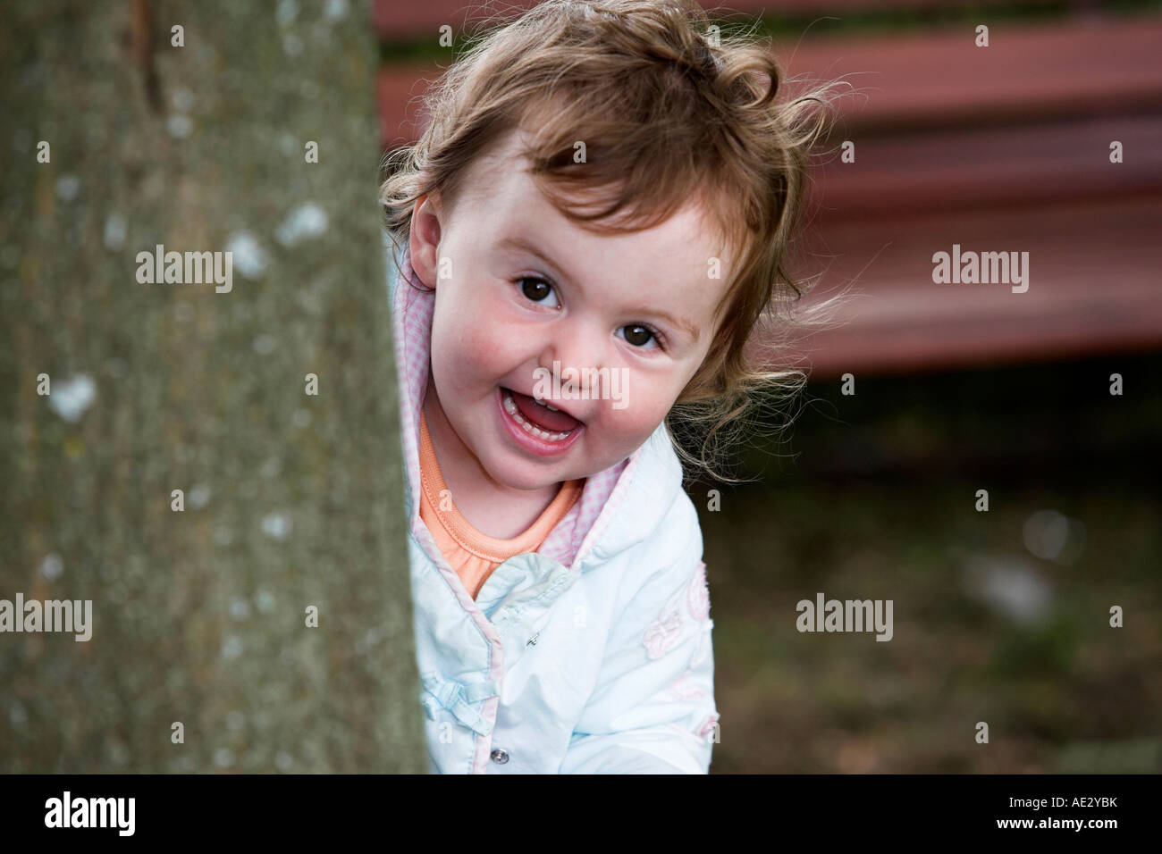 Baby Girl smiling,Tree, Baby girl hiding behind tree Stock Photo - Alamy
