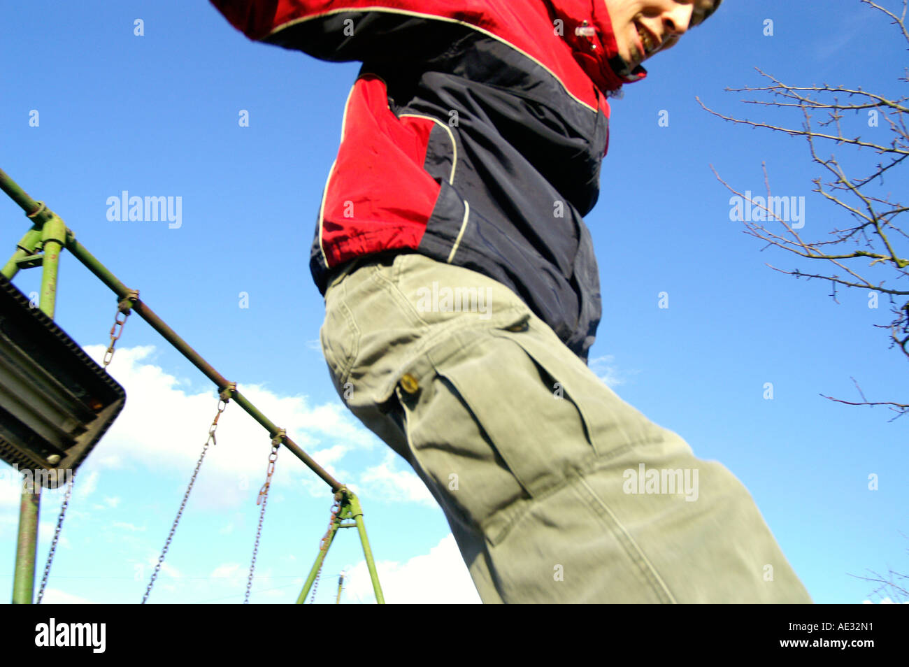 Man in 20s swinging on a swing, children playground outdoors Stock ...