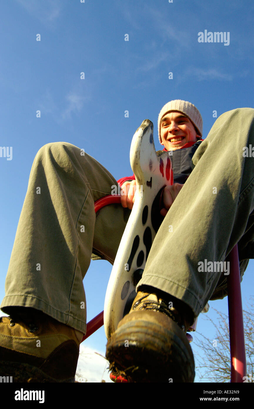 Man in 20s swinging on a rocking horse, children playground outdoors ...