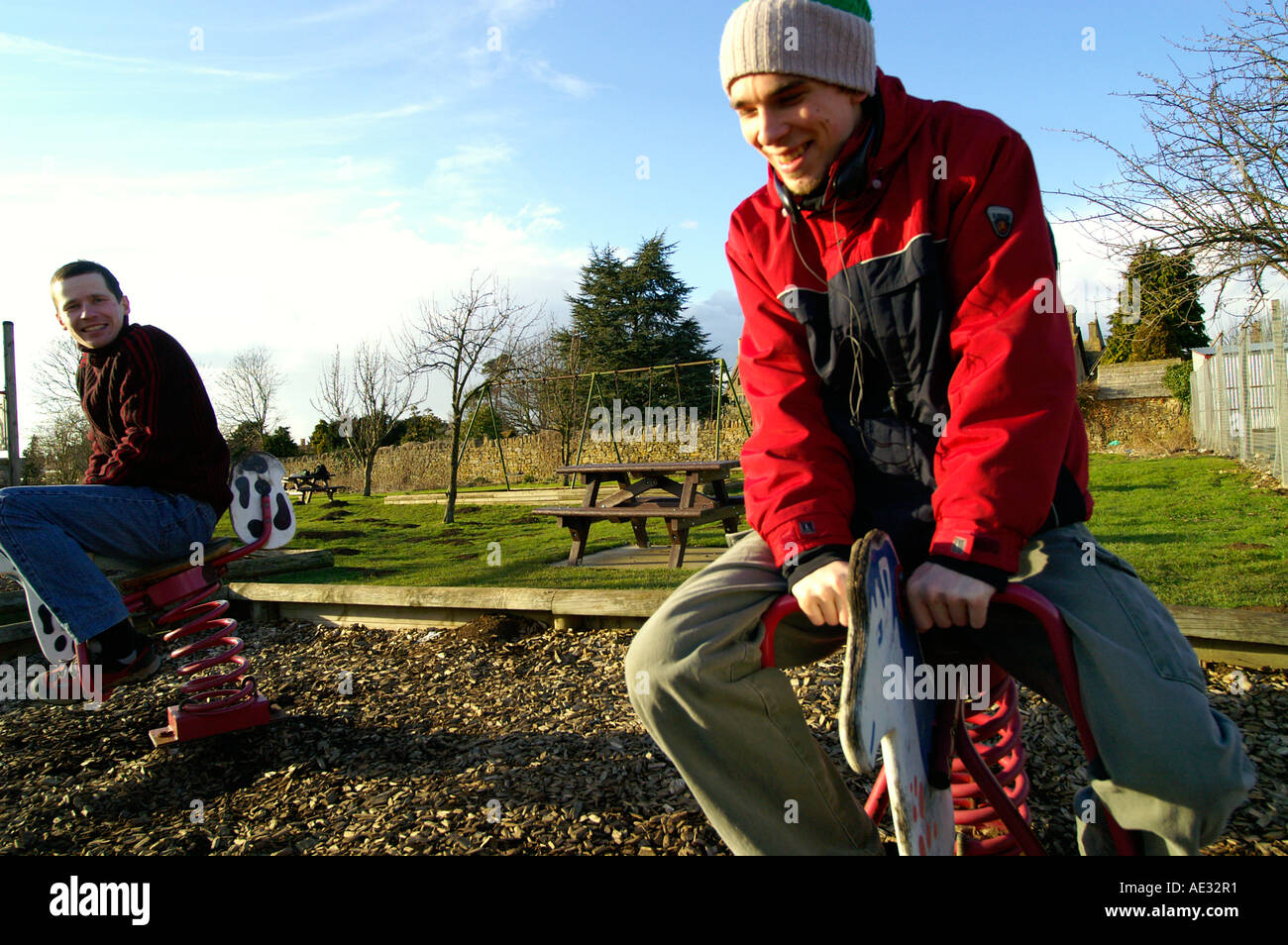Two men in 20s swinging on a seesaw, children playground outdoors Stock ...