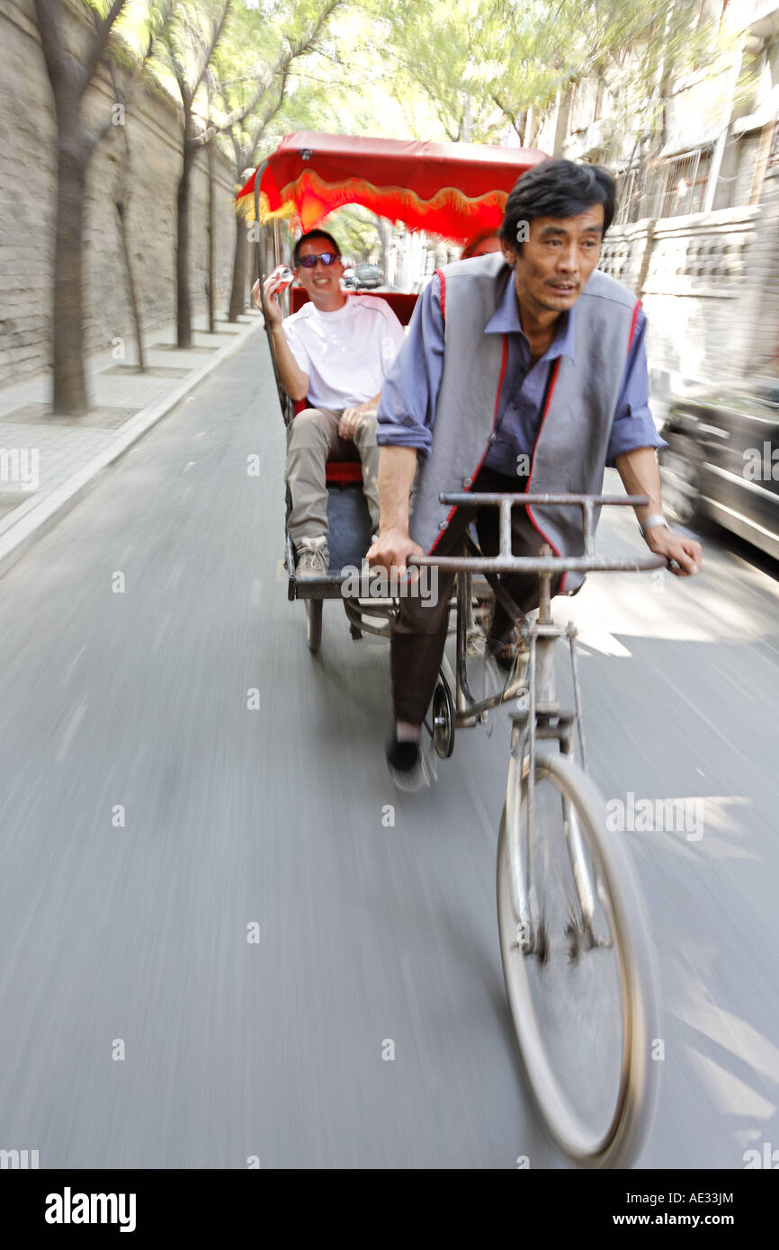 A pedicab driver gives a tourist a rickshaw ride through a Beijing ...