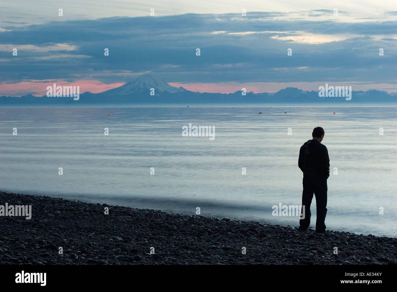 A beach of Cook Inlet, Alaska, sunset time with a silhouette of a guy ...