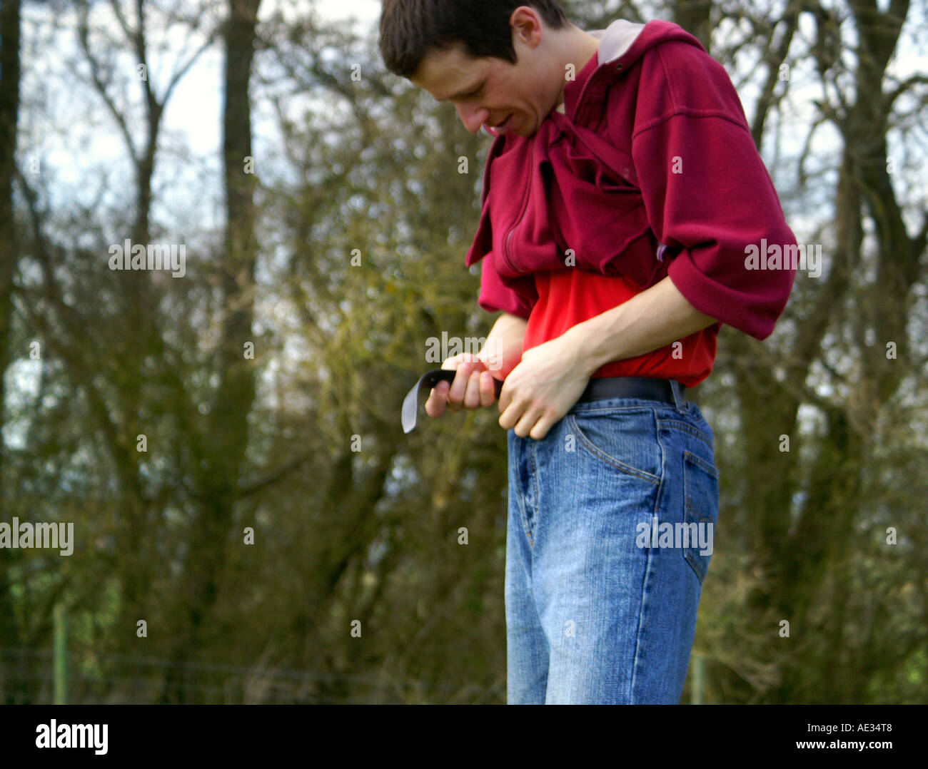Slender man tightening his belt outdoors Stock Photo - Alamy