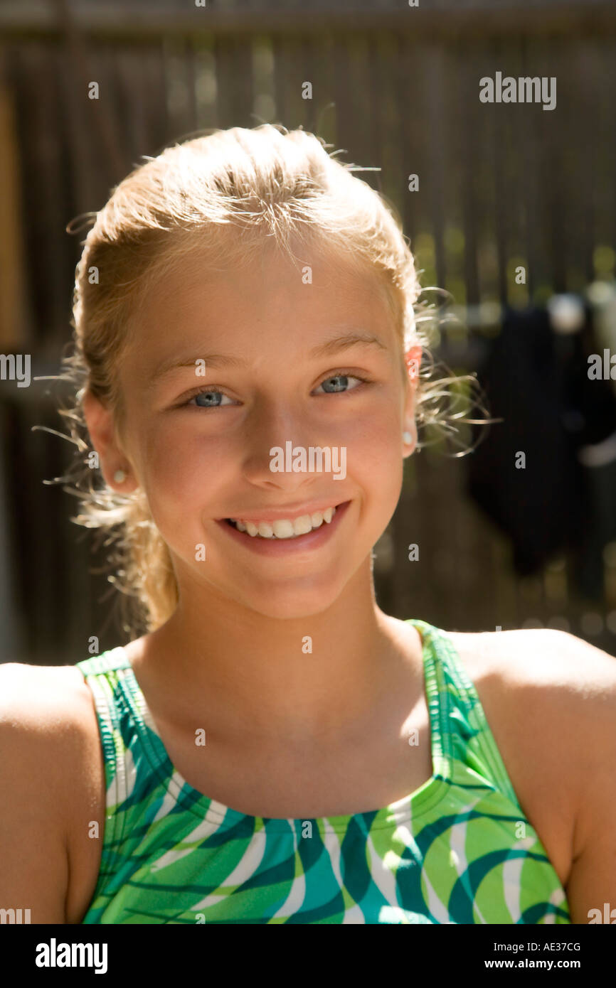 A pretty smiling, Caucasian female (12) is sitting outside in the sun ...
