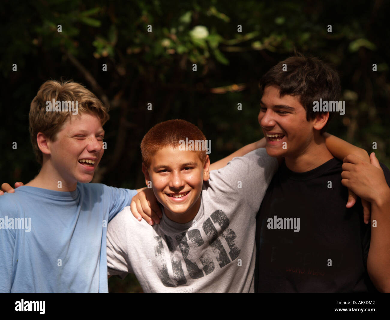 three teenage boys arms around shoulders laughing Stock Photo - Alamy