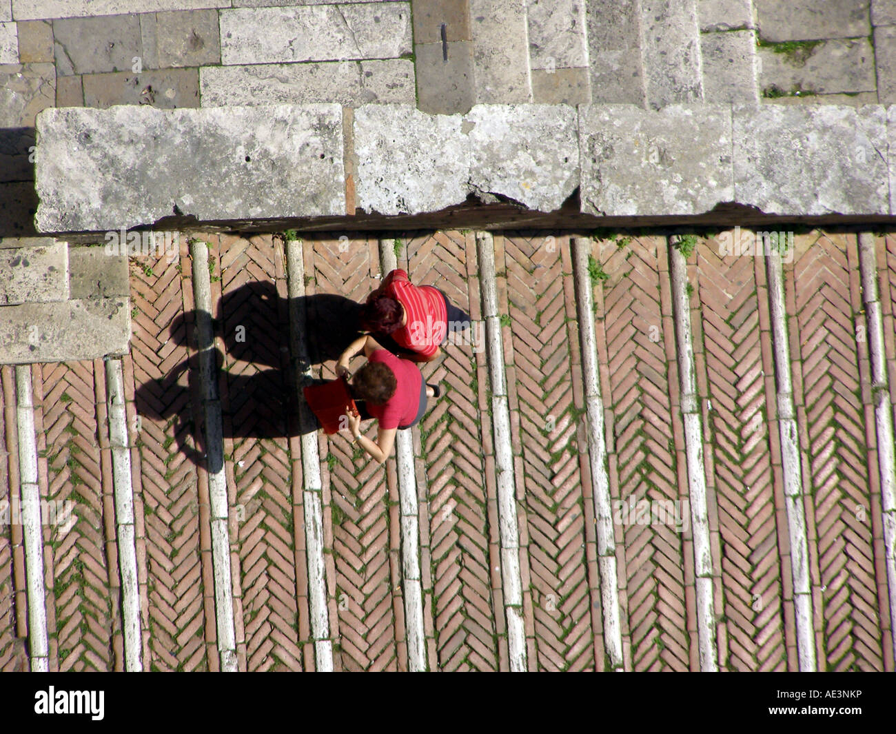 overhead view of shadows of pedestrians in red walking up steps paved ...