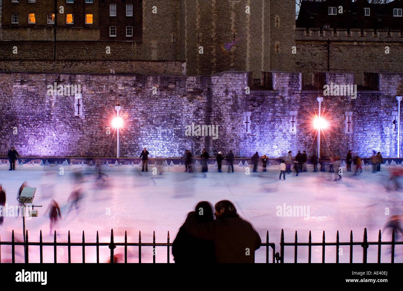 Couple watching skaters on the ice rink next to The Tower of London ...