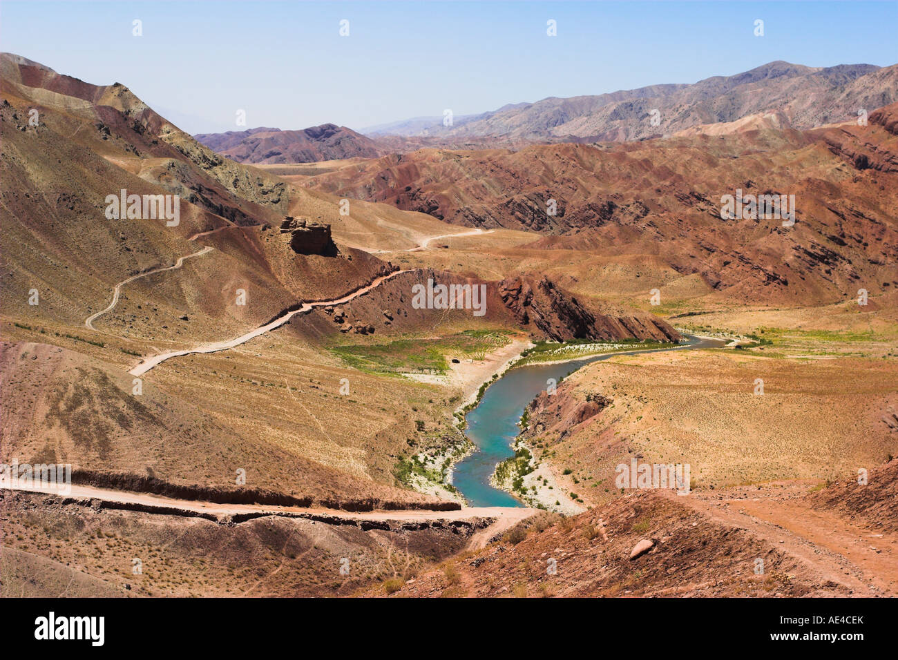 Hari Rud river through fertile valley at base of red rock mountains ...