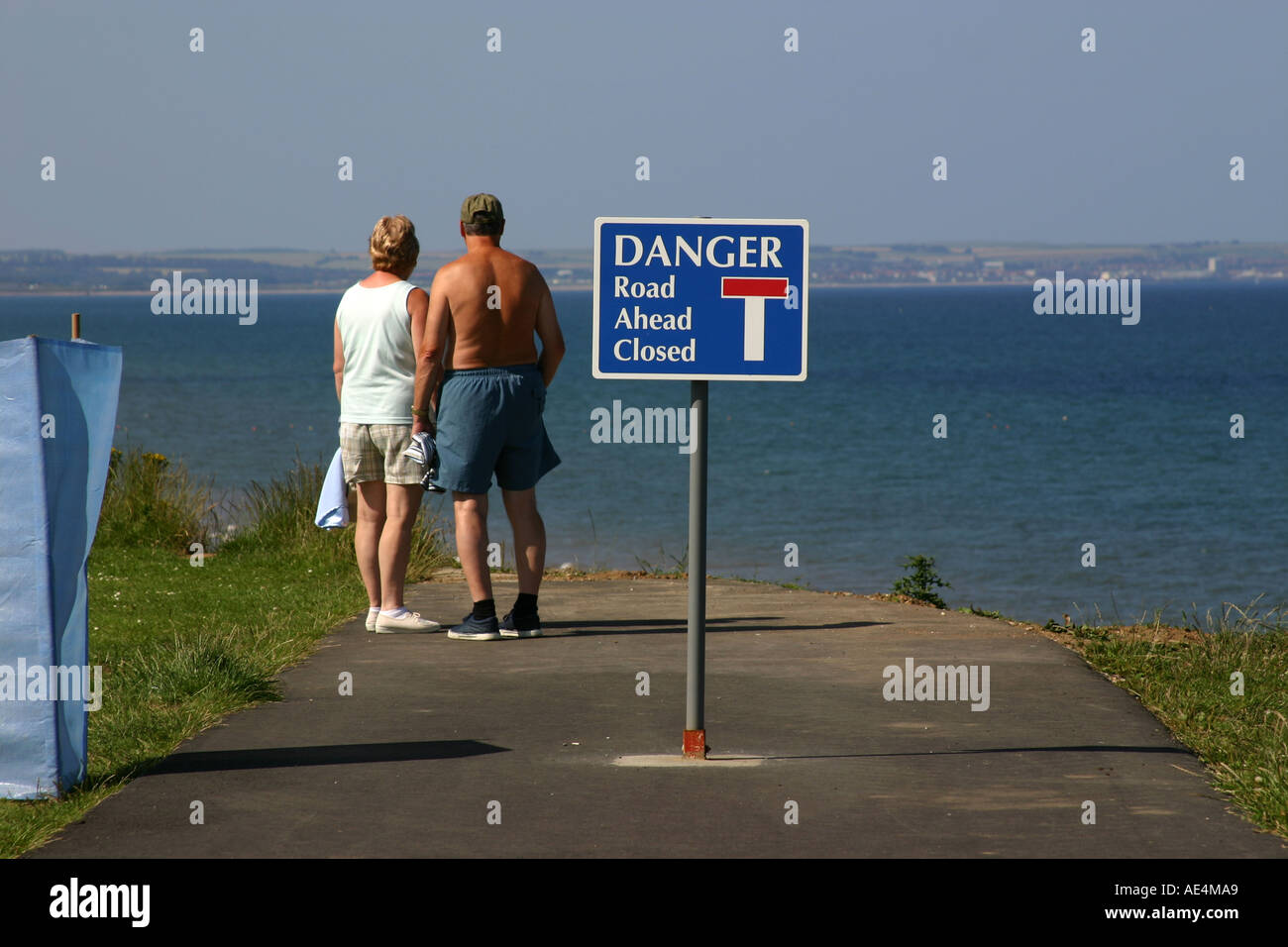 Man and woman studying sign stating end of road which is actually very ...