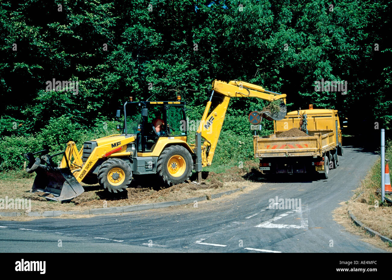 MF Excavator construction plant loading a lorry truck with earth spoil ...