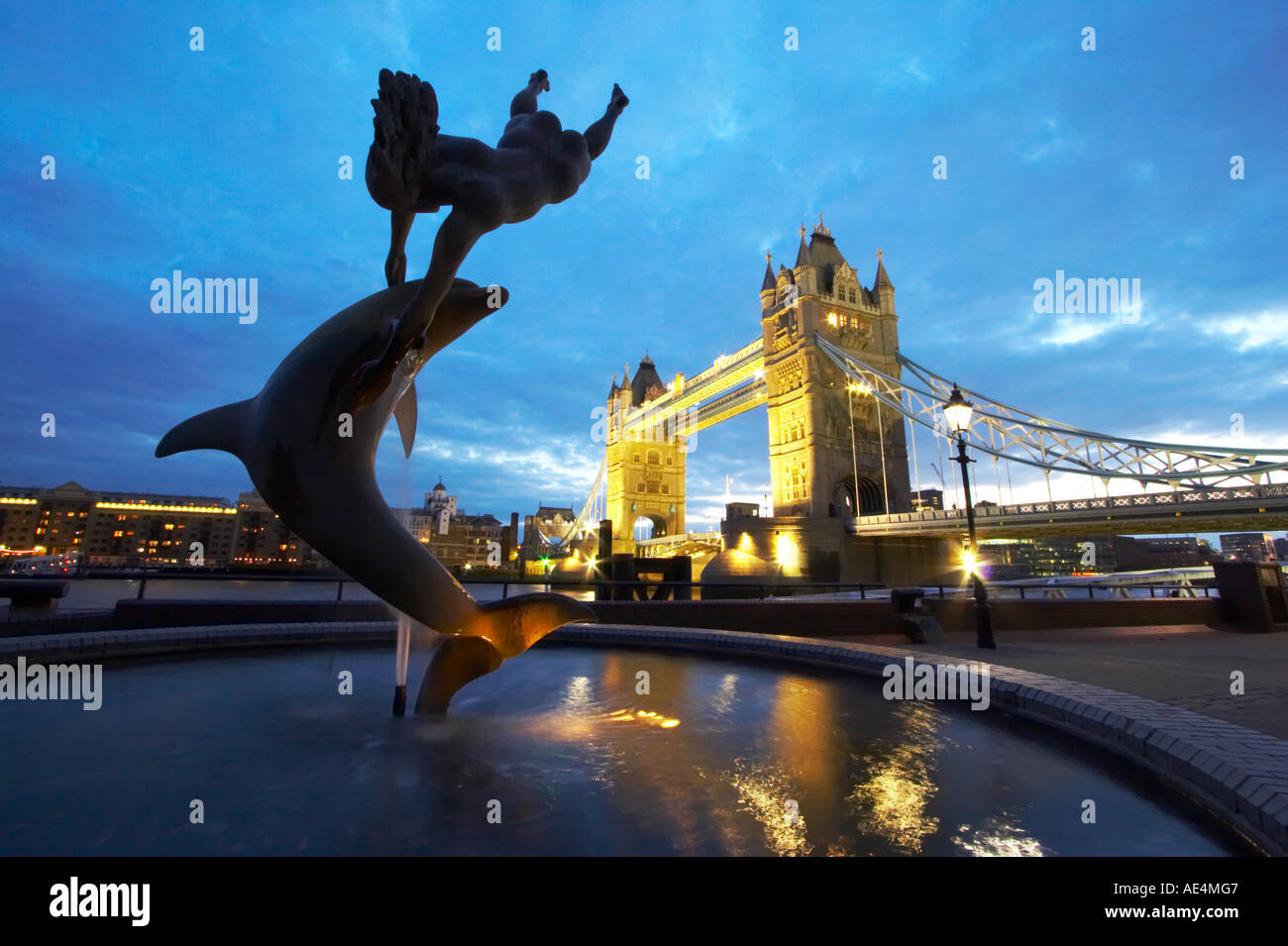 Tower Bridge illuminated at night with Maid and Dolphin statue, London ...