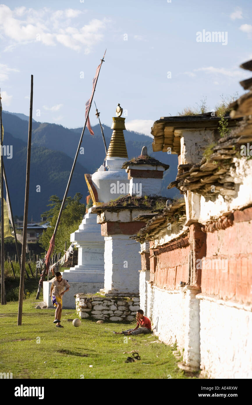 Bhutanese boys playing soccer near Buddhist chortens (stupa), Paro ...