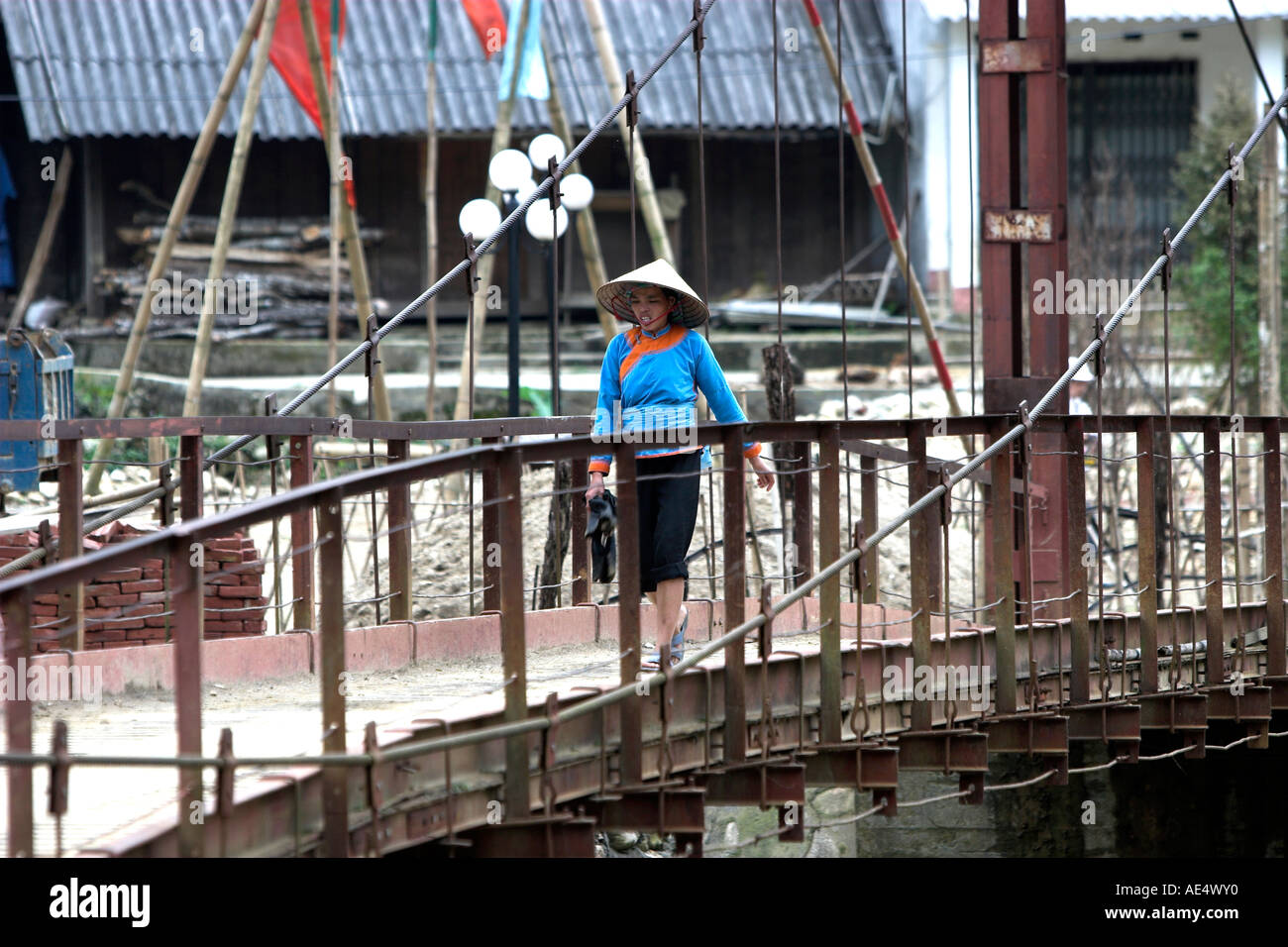 Zay woman in traditional clothing and conical hat crosses bridge Ta Van ...