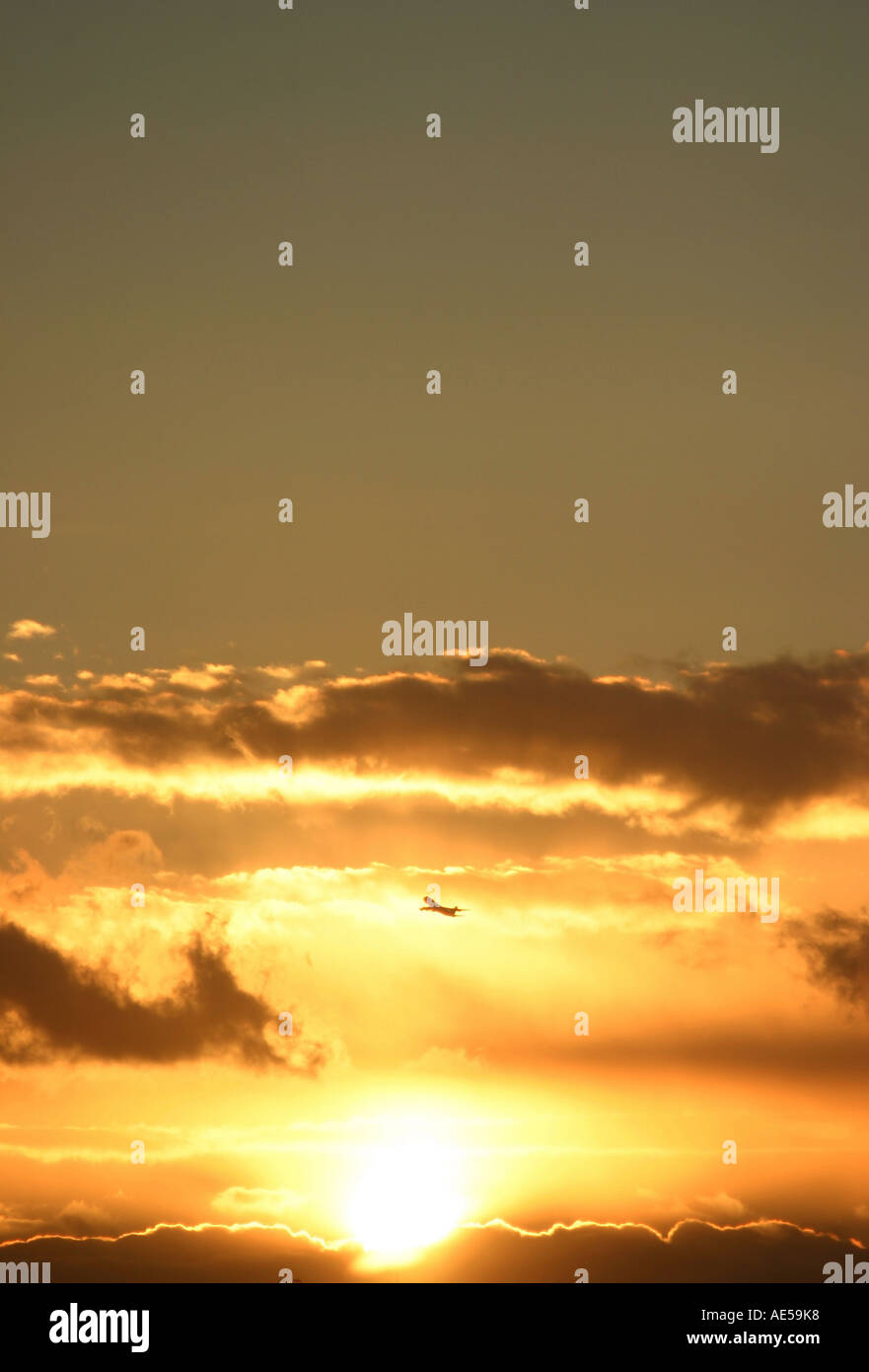 Airplane flying into the sun set Stock Photo - Alamy