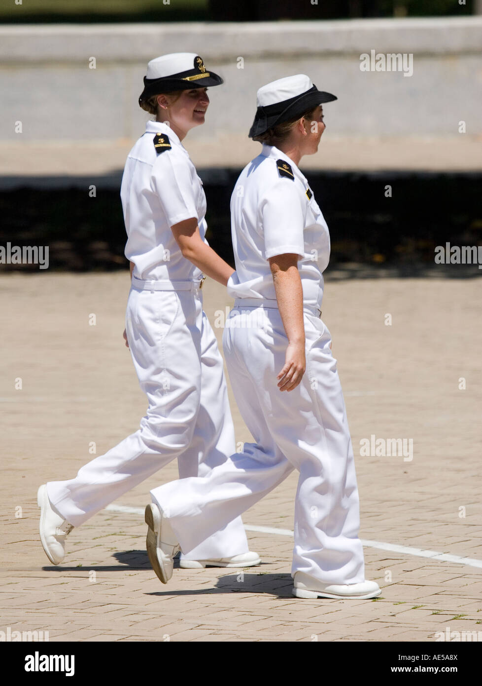 Two female sailors in white service uniforms walking on the campus of ...