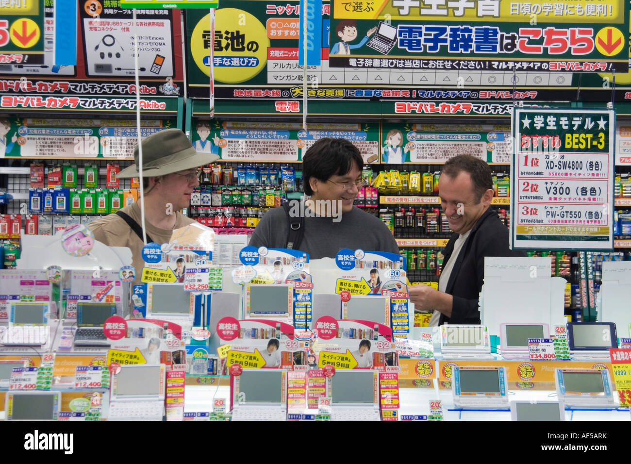 Men behind clutter of electronics gadgets and Japanese signs ...
