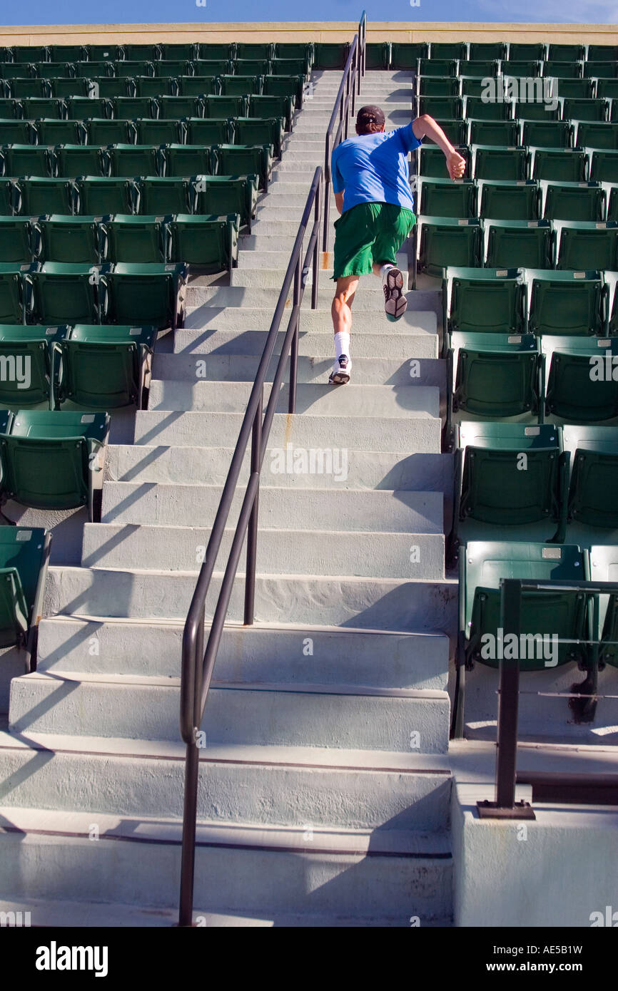 Man in his 20s running up the steep concrete steps of an aisle in an ...