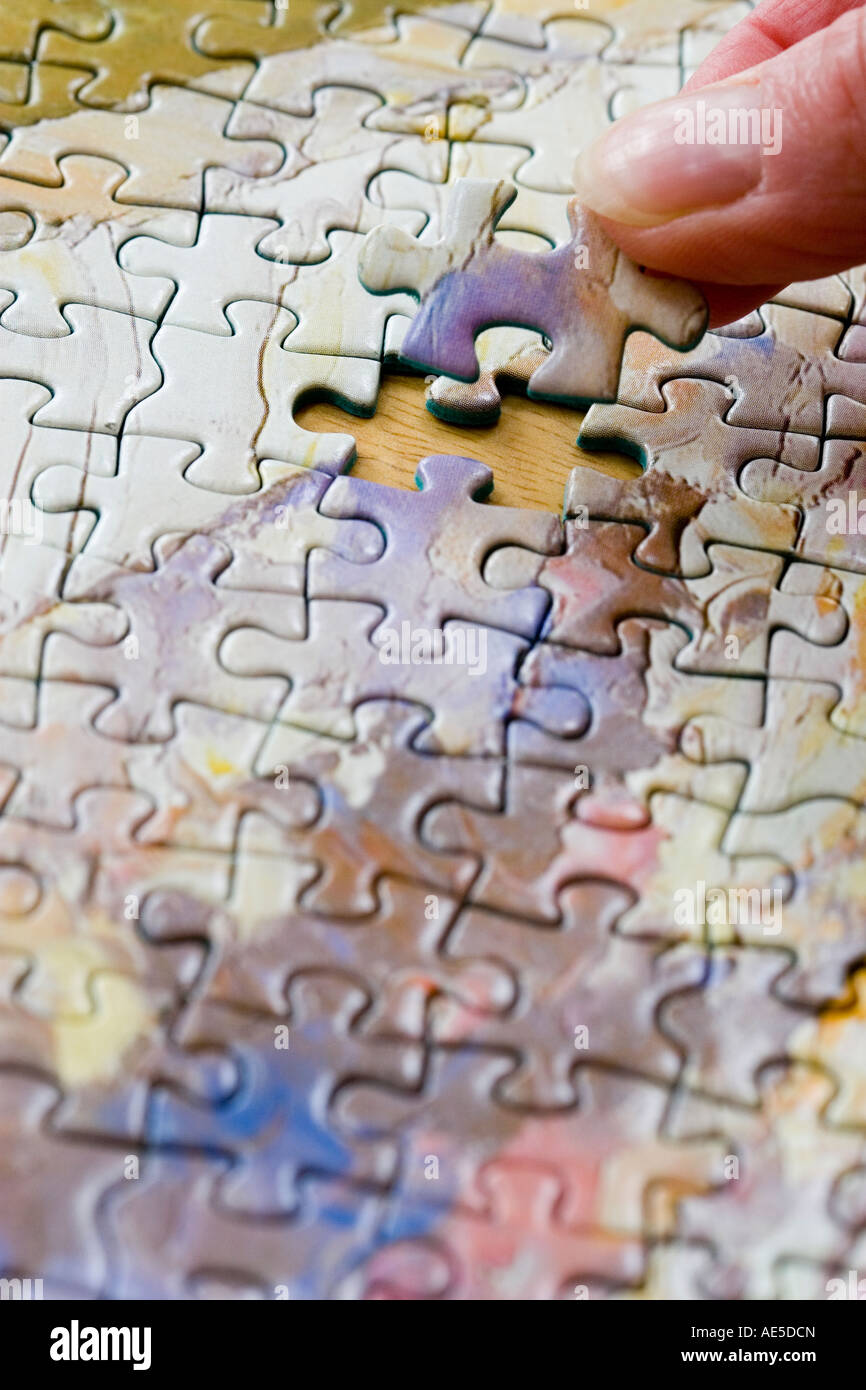 Jigsaw puzzle pieces connected together with hand putting in the last ...