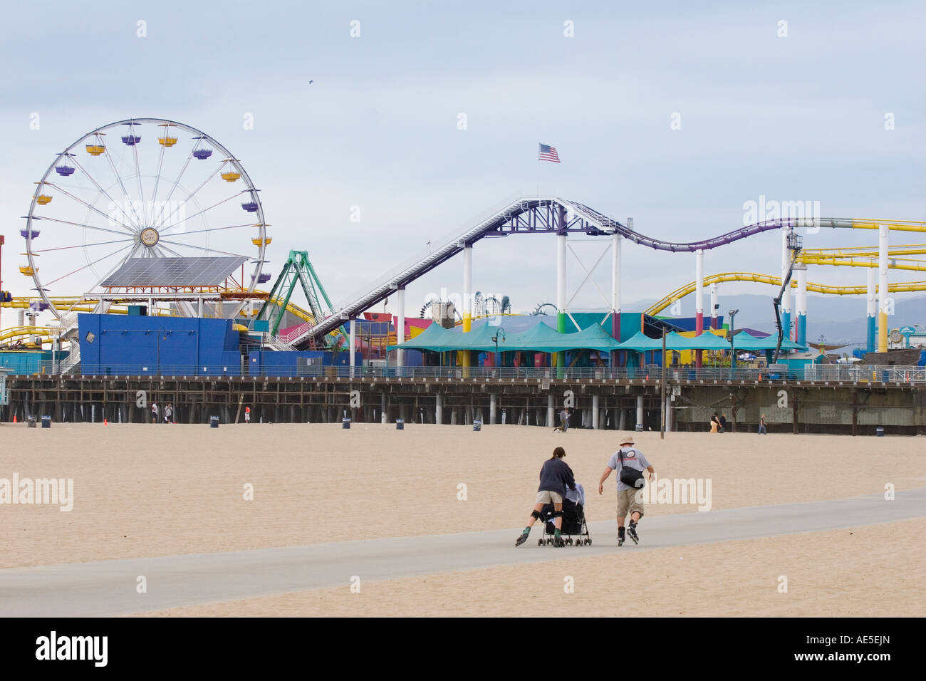 Parents rollerblading and pushing a stroller on path along beach at ...