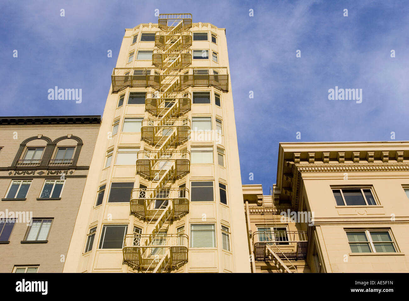 Looking up at tall residential buildings with fire escapes in affluent ...