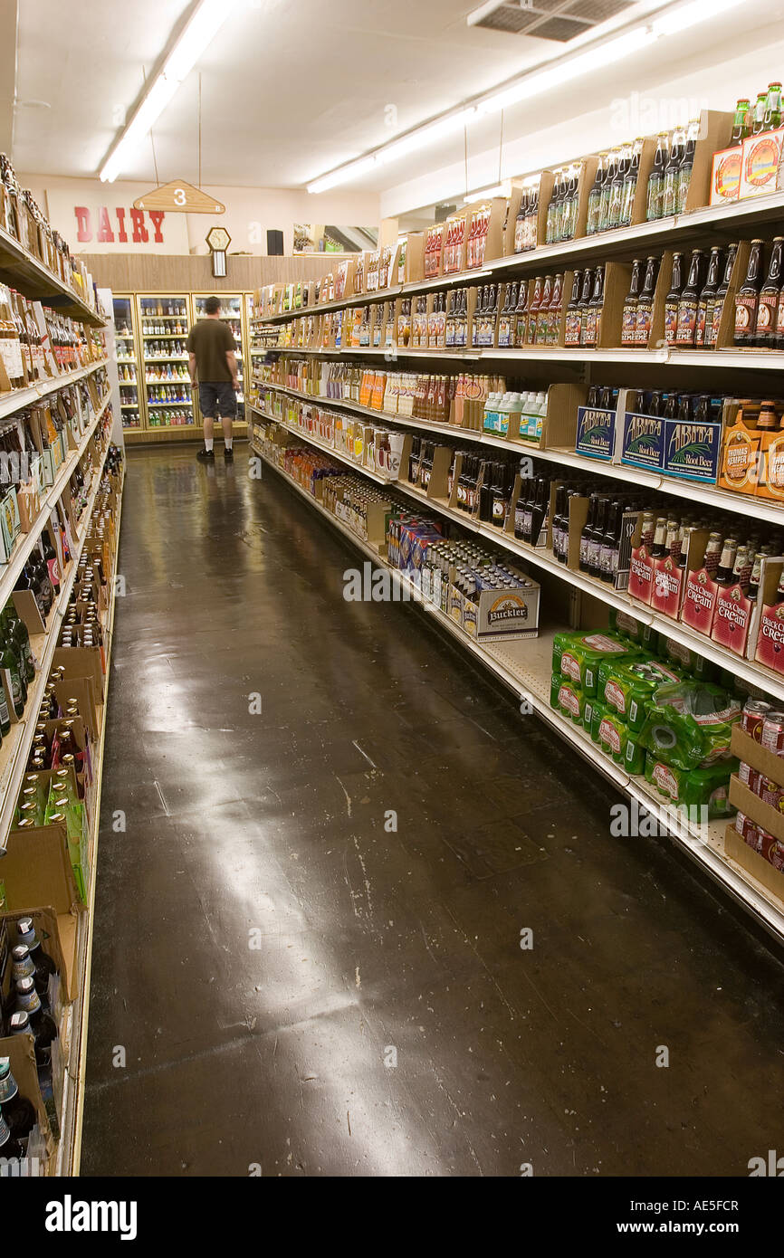 Man shopping for soda and beer in beverage store aisle with large ...