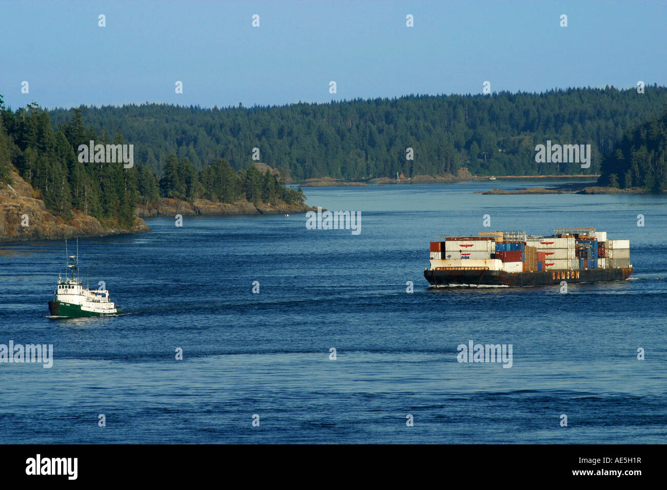 Tug boat pulling giant barge filled with cargo boxes down the Inside ...