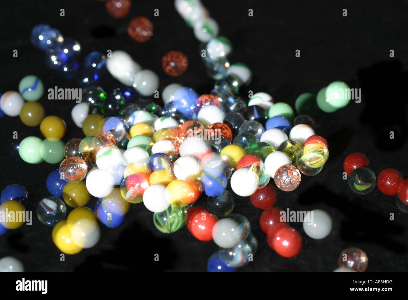 Marbles of many colors scattering in all directions after being hit ...