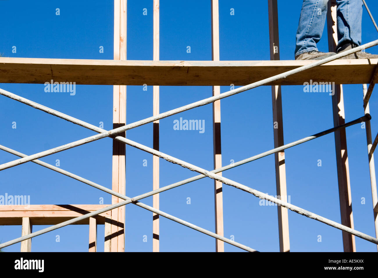 Legs and feet of carpenter standing on scaffolding next to the studs of ...