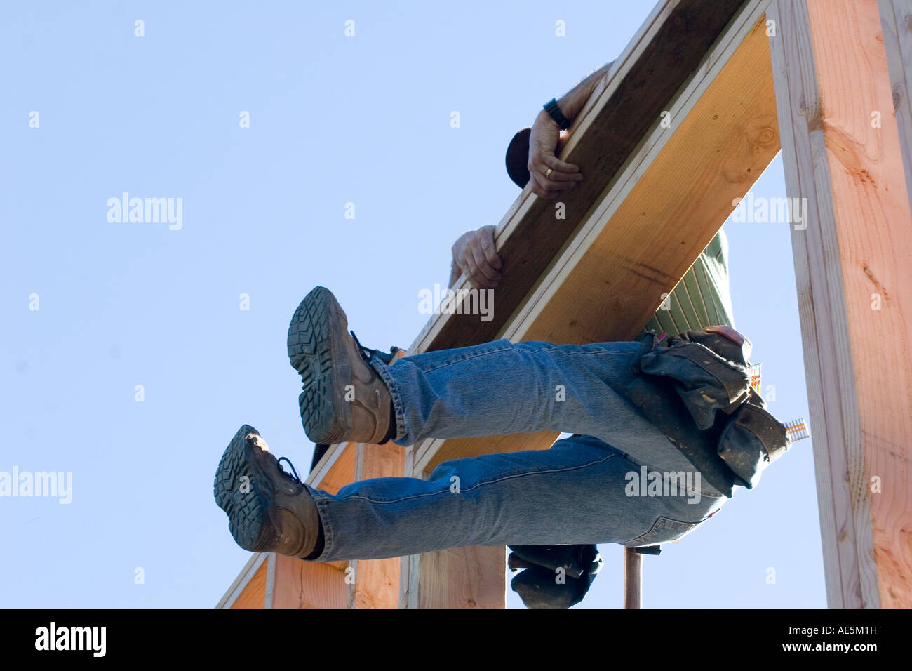 Carpenter with tool belt dangling from window frame in a moment of ...