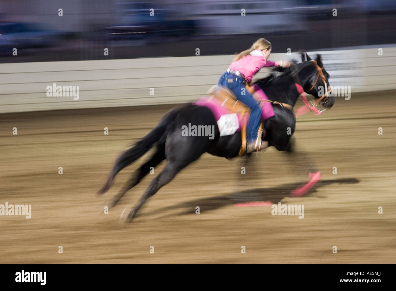 Teenage girl dressed in pink racing on her horse in a blur as they ...
