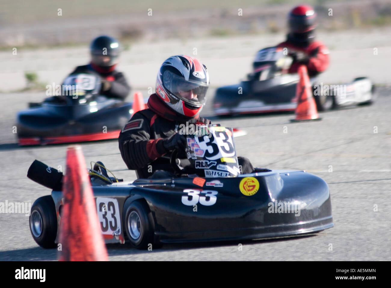 Three go kart racers racing around a curve with orange cones on an ...
