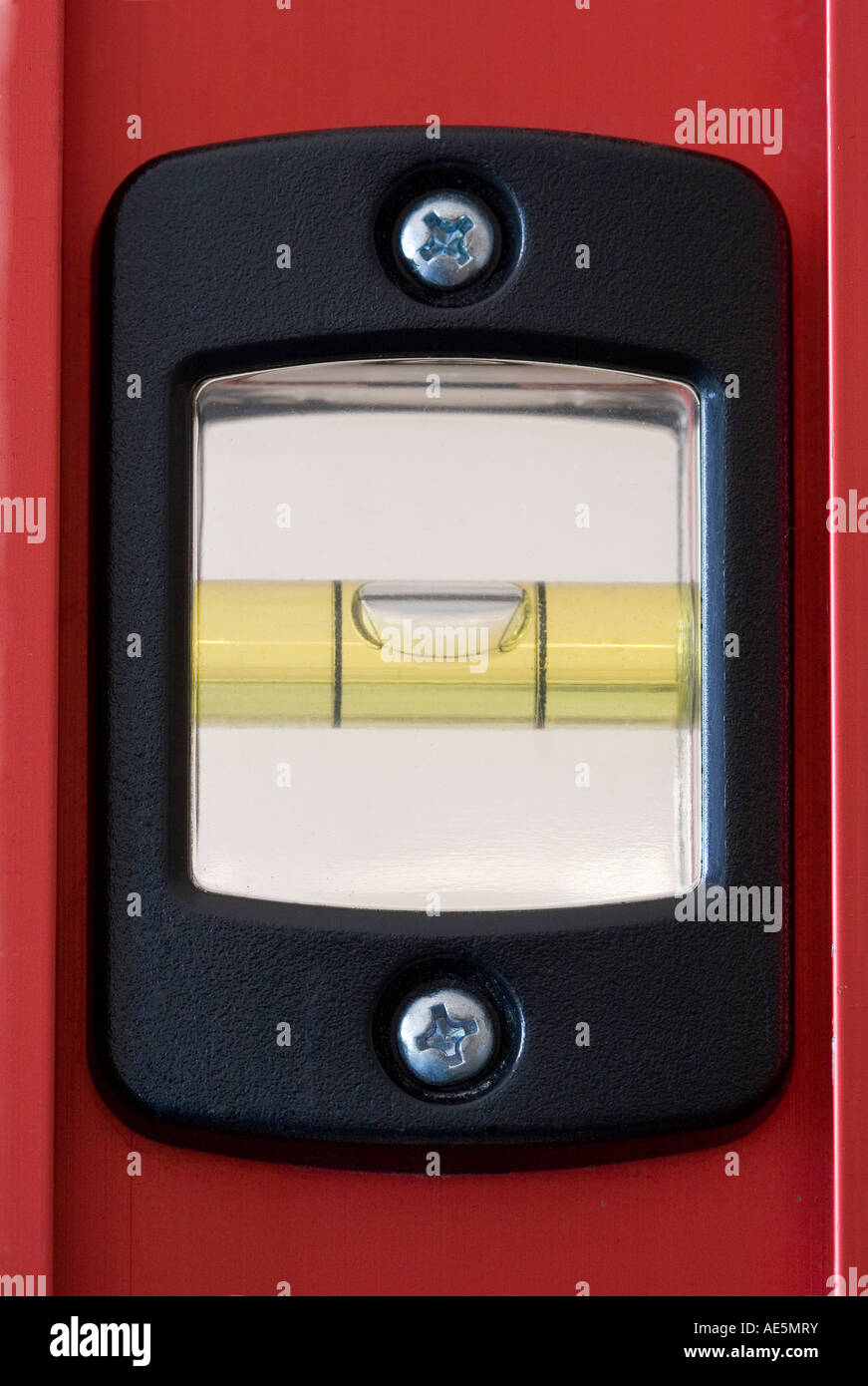 Vertically oriented red metal level tool showing the bubble in the ...
