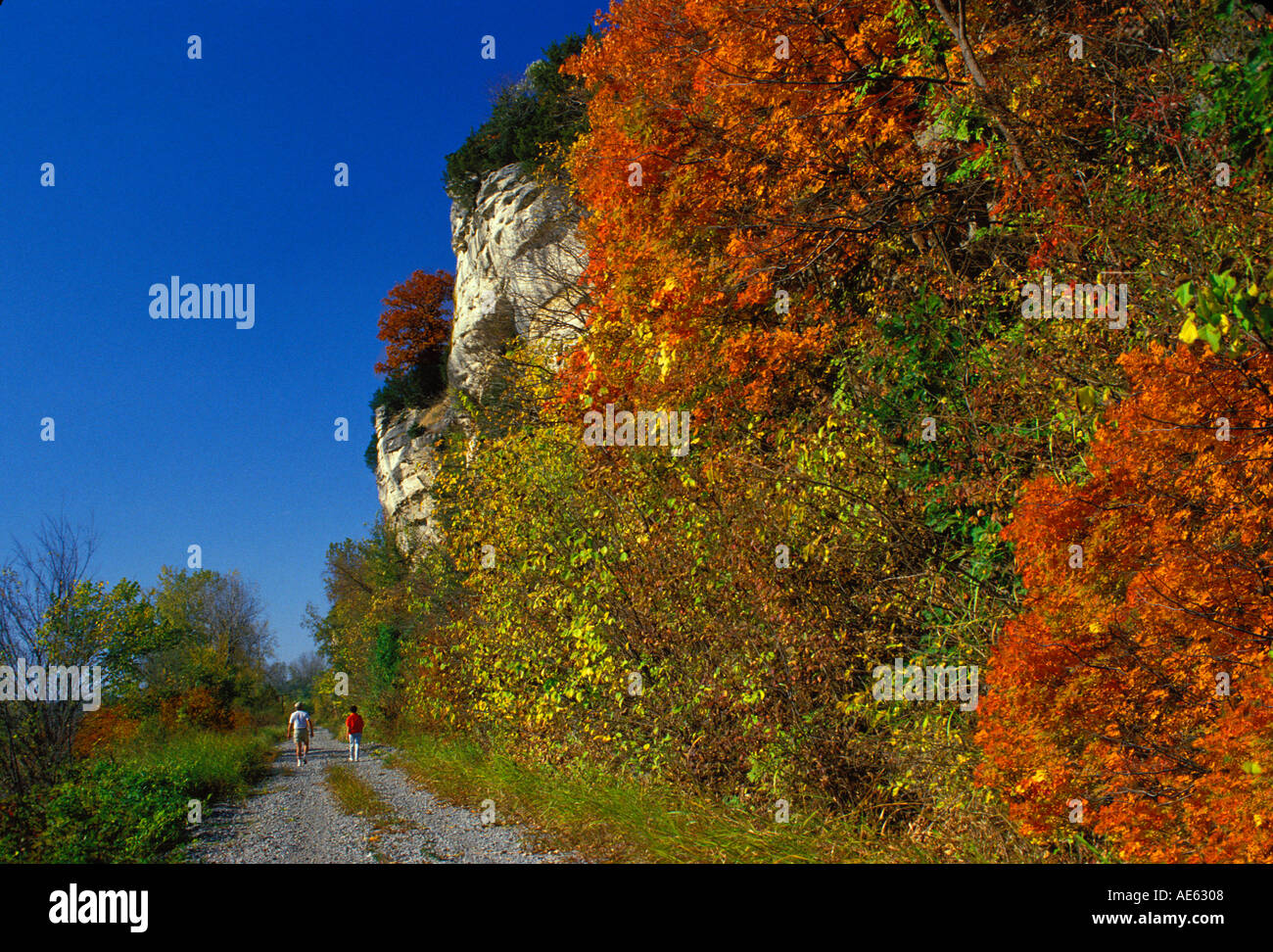 People walking along scenic trail along base of limestone cliffs in ...