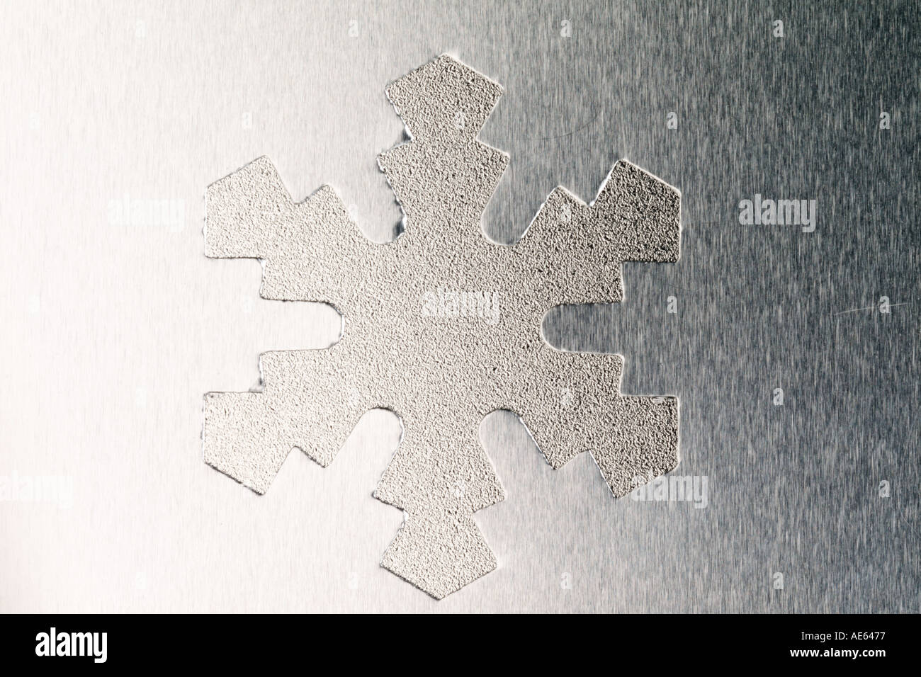 metallic snowflake punched out of thin brushed sheet metal Stock Photo ...
