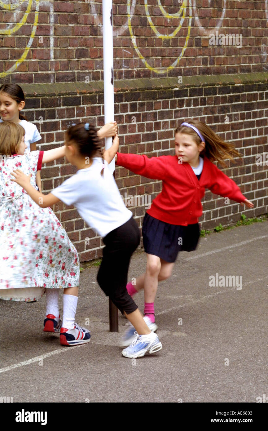 Primary school girls twirling round pole in playground Stock Photo - Alamy